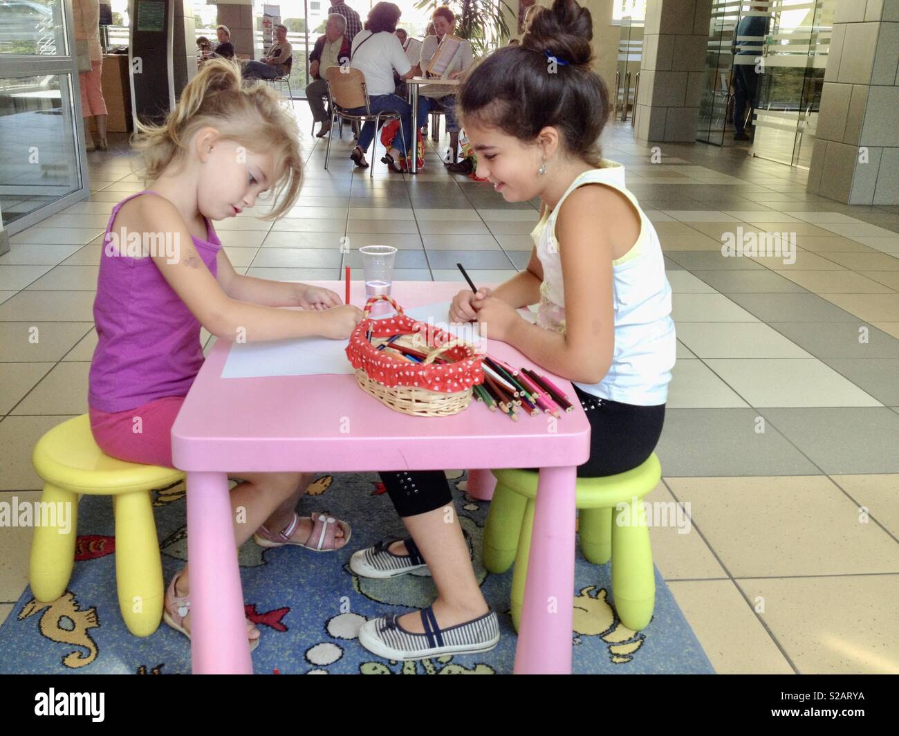 Two girls drowning together beside small pink plastic table Stock Photo ...
