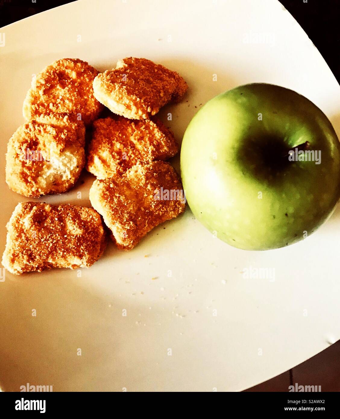 Shiny green apple on a white plate with golden chicken nuggets Stock ...
