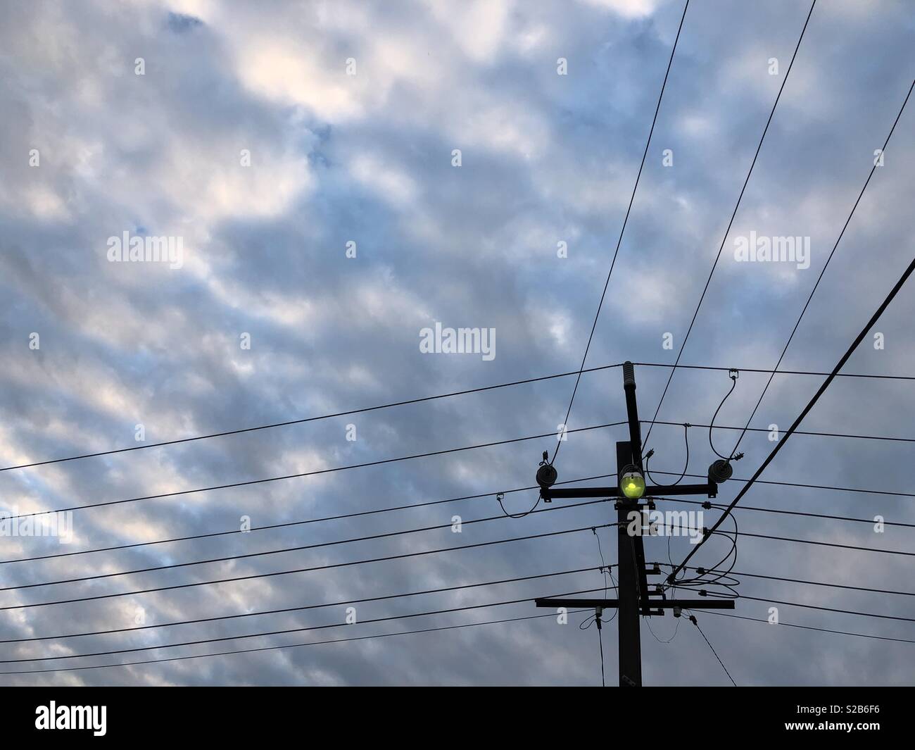 Power lines and street light under a cloudy sky Stock Photo - Alamy