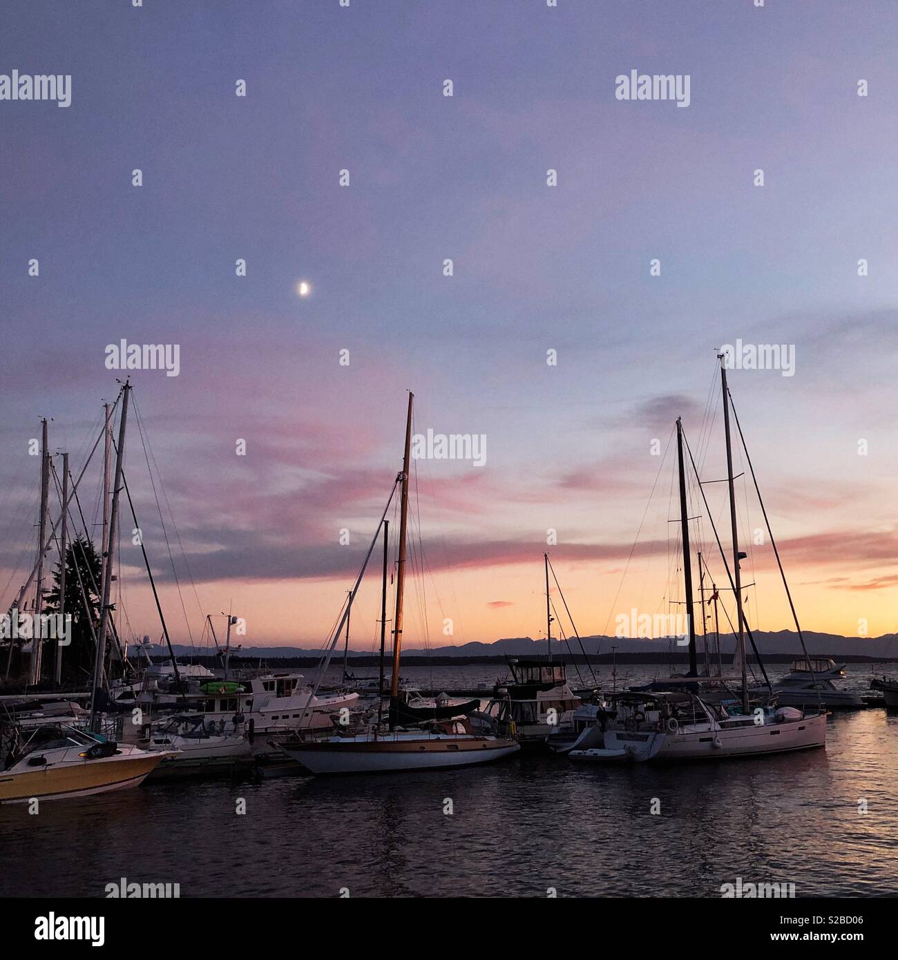 New moon and sunset above Vancouver Island seen from Lund marina Stock ...