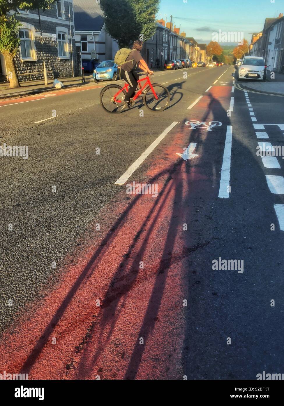 Cyclist crossing a road with shadow of another cyclist on a cycle lane ...
