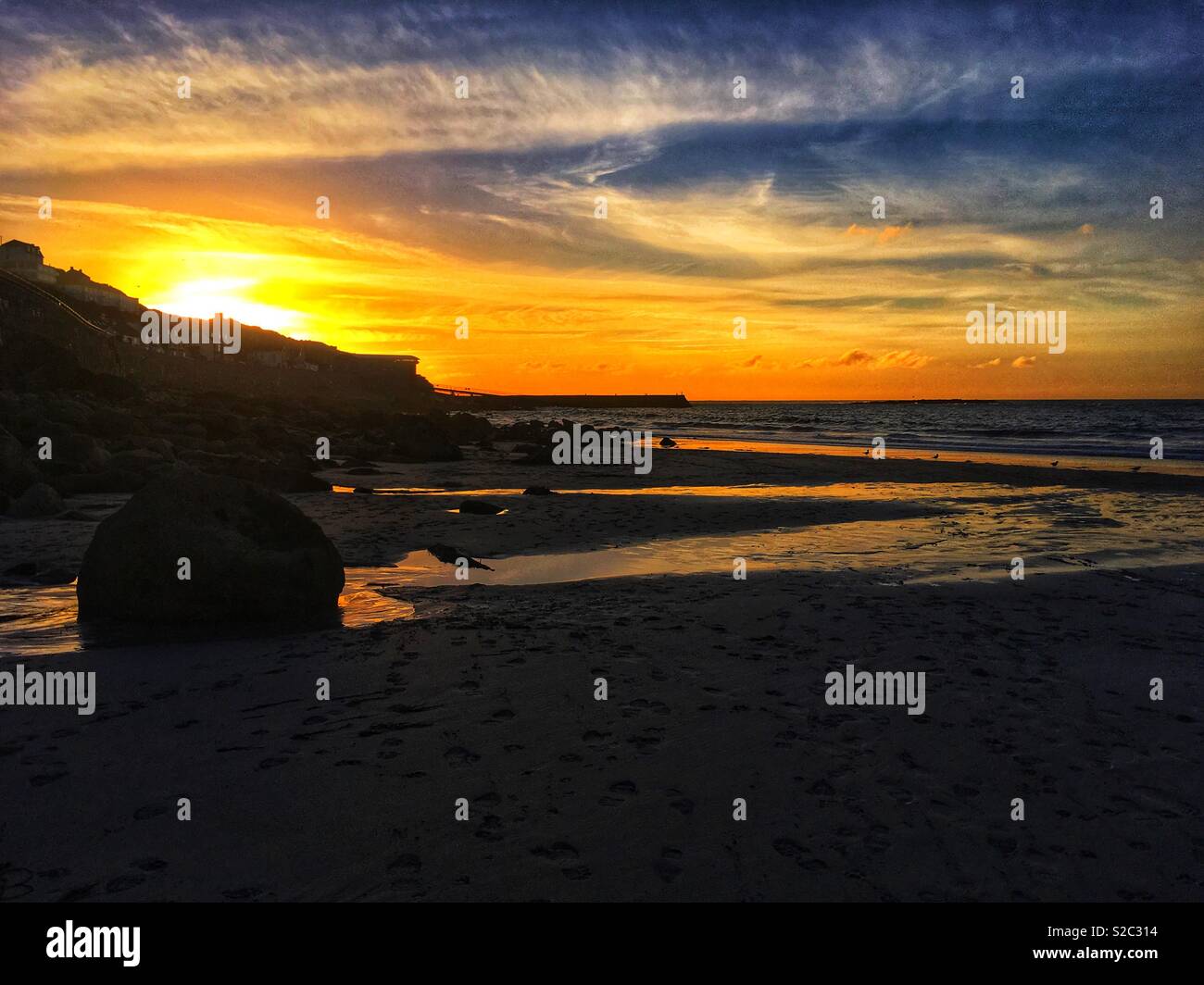 Sunset on a beach in Cornwall with bright sky and reflections Stock ...