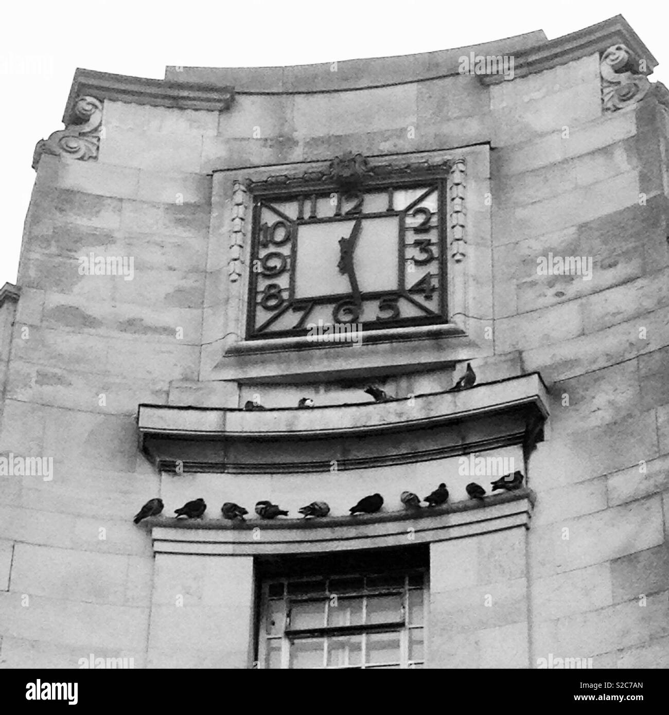 Pigeons sitting on a ledge beneath an Art Deco clock face Stock Photo ...