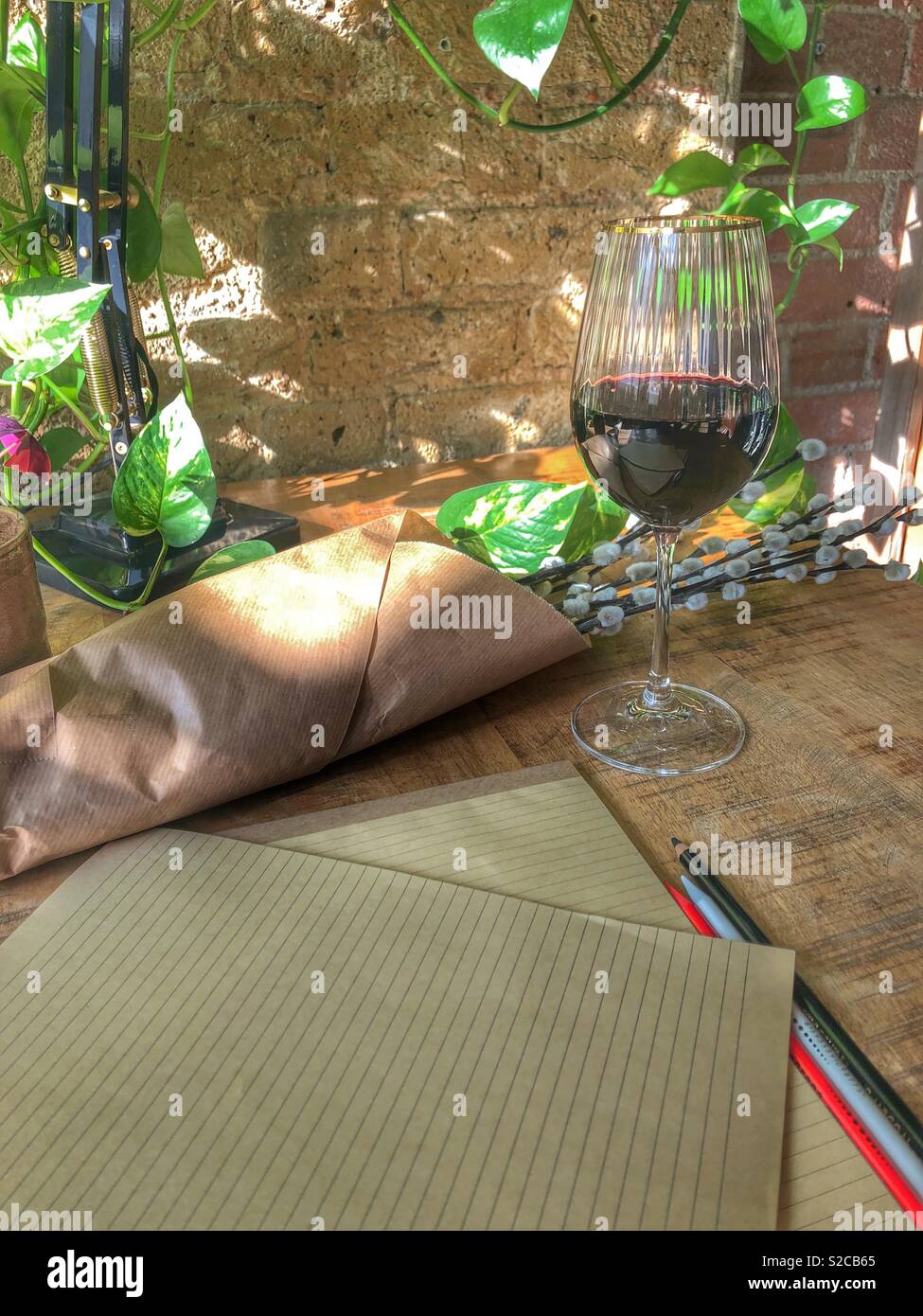 Desk with red wine, exposed brick and notebooks Stock Photo - Alamy