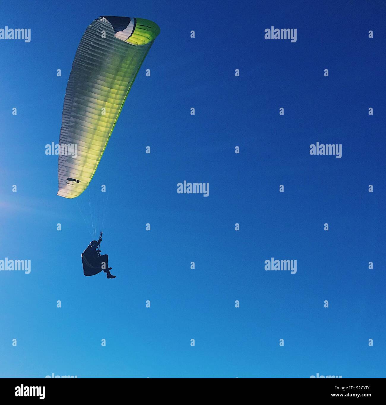 Blue sky and man paragliding Stock Photo - Alamy