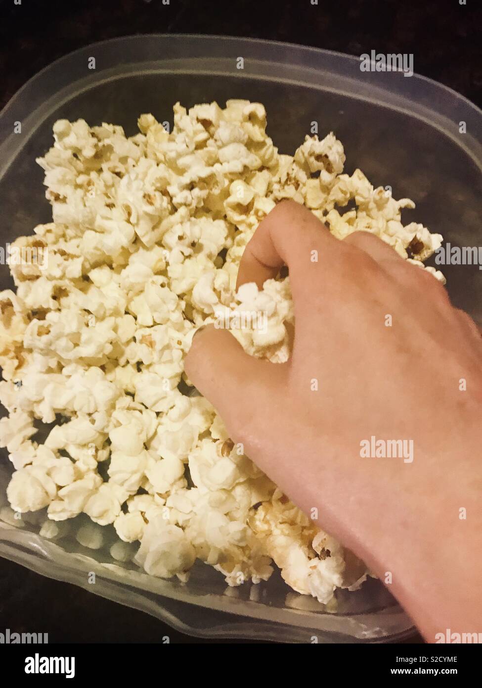 Girls hand Reaching into the popcorn bowl Stock Photo - Alamy
