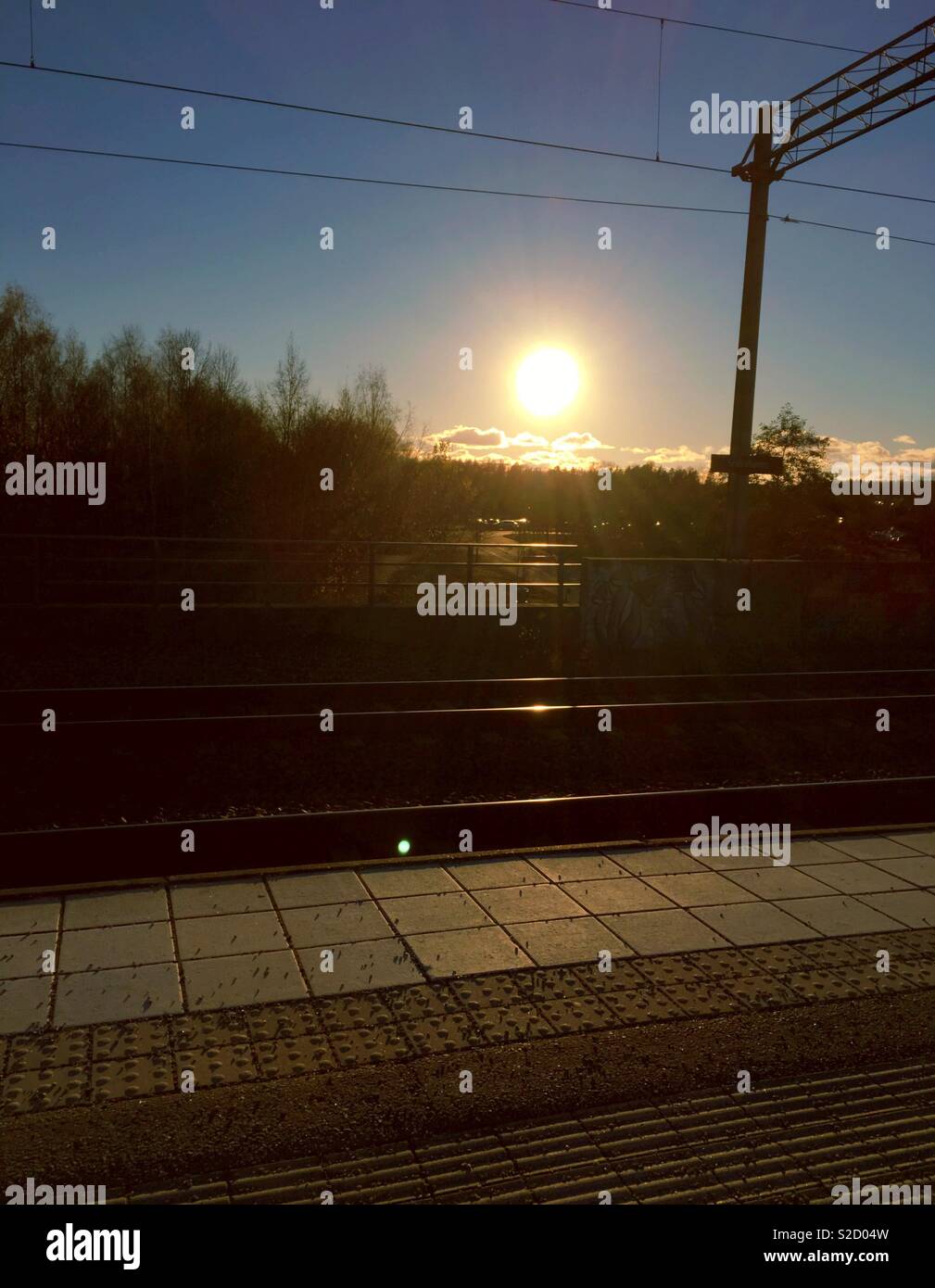 Sun goes down by a train station Stock Photo - Alamy