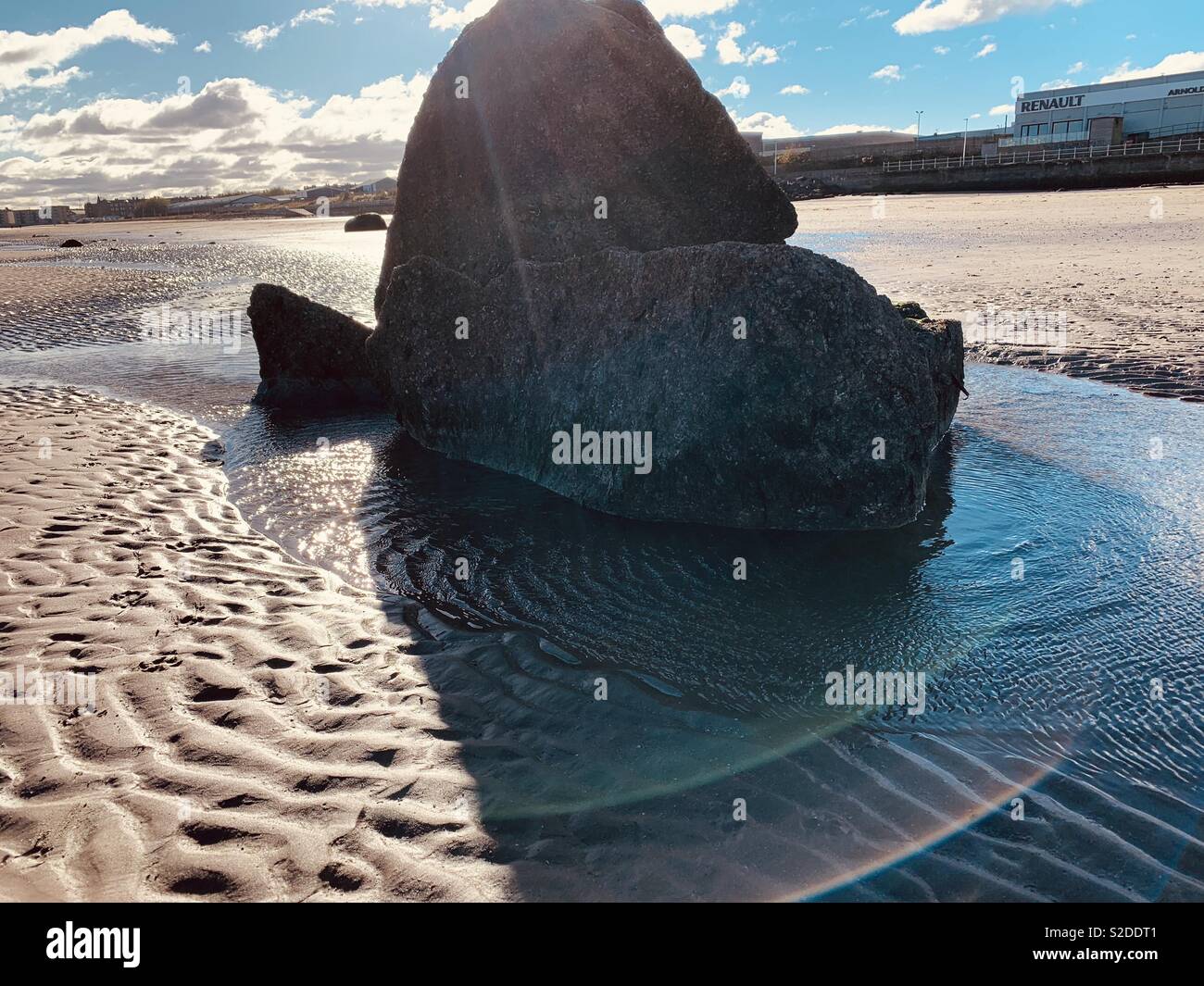 Large rocks on the beach viewed with some sun flare Stock Photo - Alamy