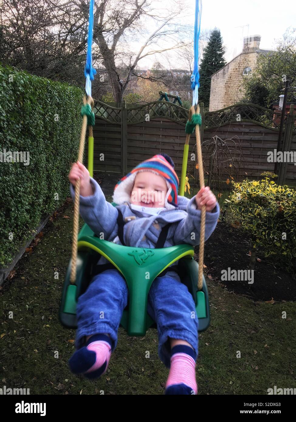 Baby boy happily swinging on his swing Stock Photo - Alamy