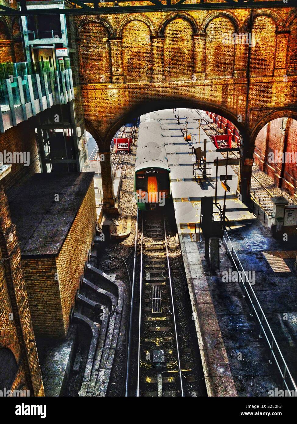 Train pulling into an old deserted Victorian rail station platform viewed from a high angle ...
