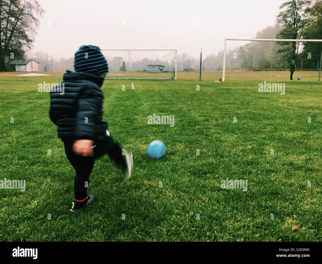 2 year old boy Kicking ball on sucker field Stock Photo - Alamy