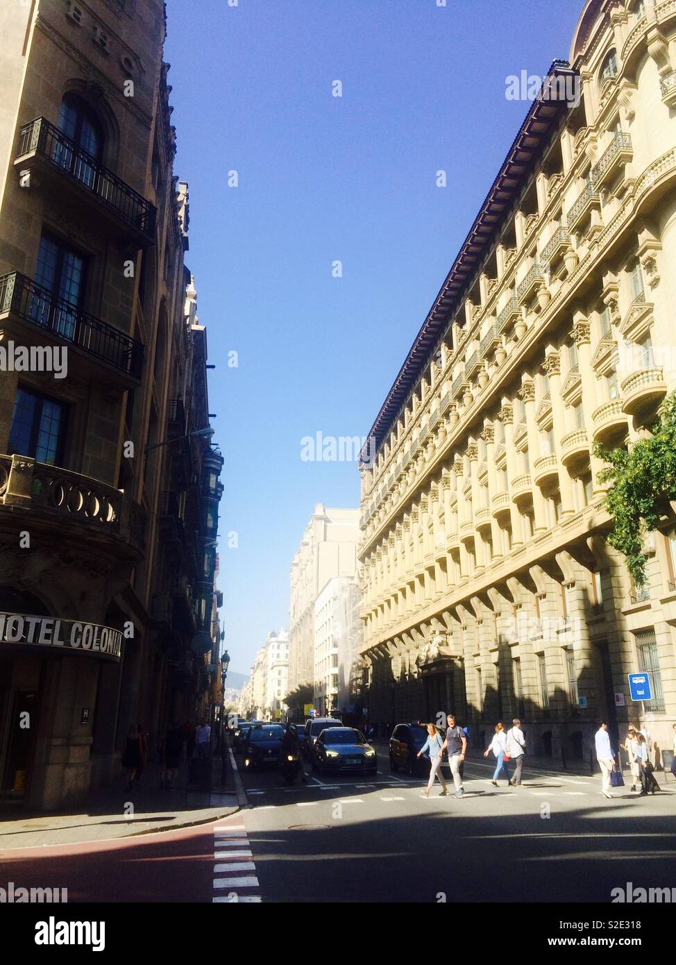 Street scene of buildings and people crossing a busy road in Barcelona ...