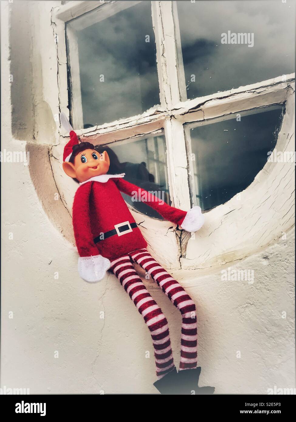 Naughty elf sitting on a window sill Stock Photo - Alamy
