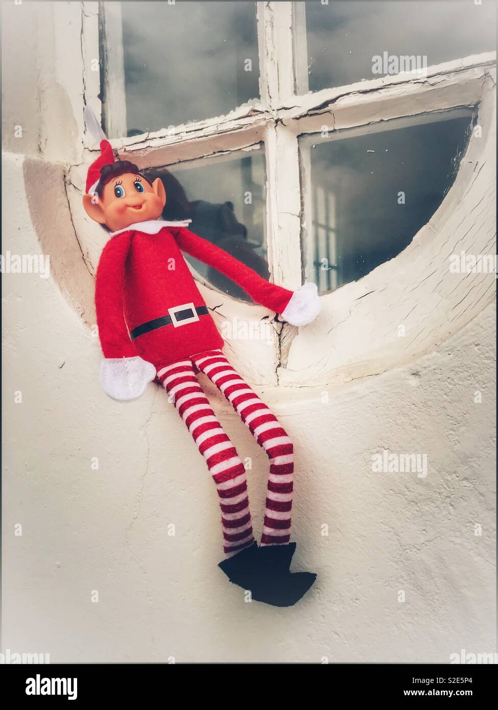 Naughty elf sitting on a window sill Stock Photo - Alamy