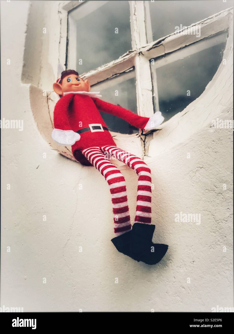 Naughty elf sitting on a window sill Stock Photo - Alamy