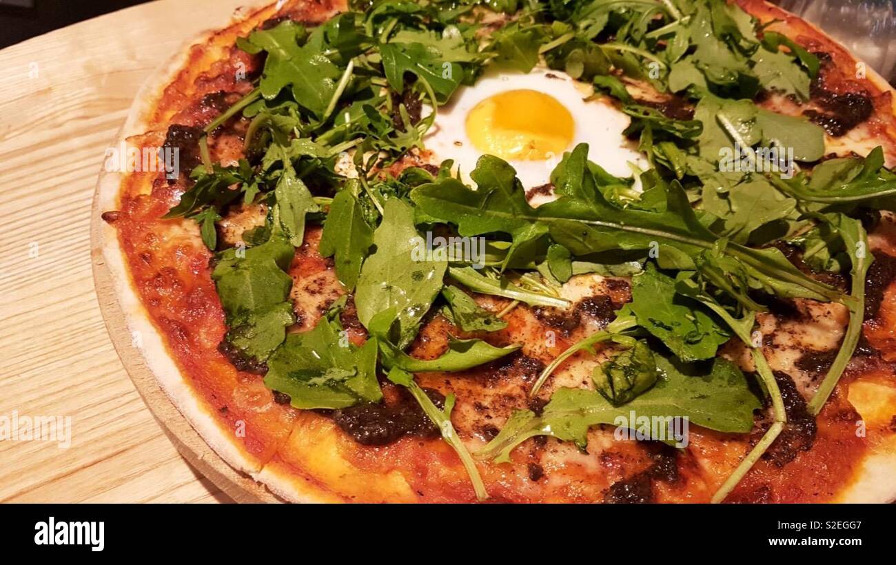 Thin crust pharma ham wild rocket egg pizza Stock Photo - Alamy