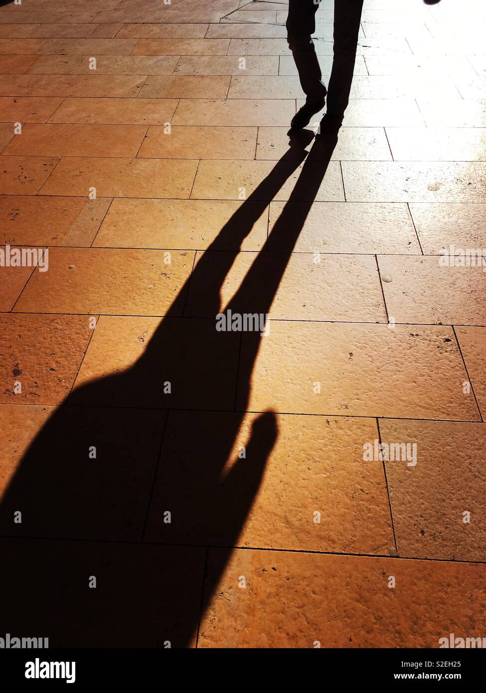 Shadows of lone man on pavement Stock Photo - Alamy