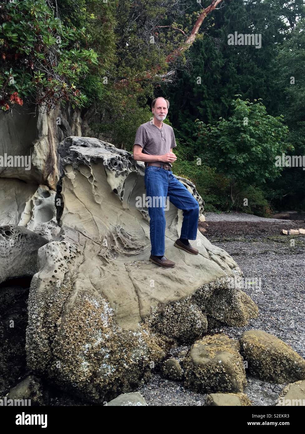 Man on barnacle covered rock Stock Photo - Alamy