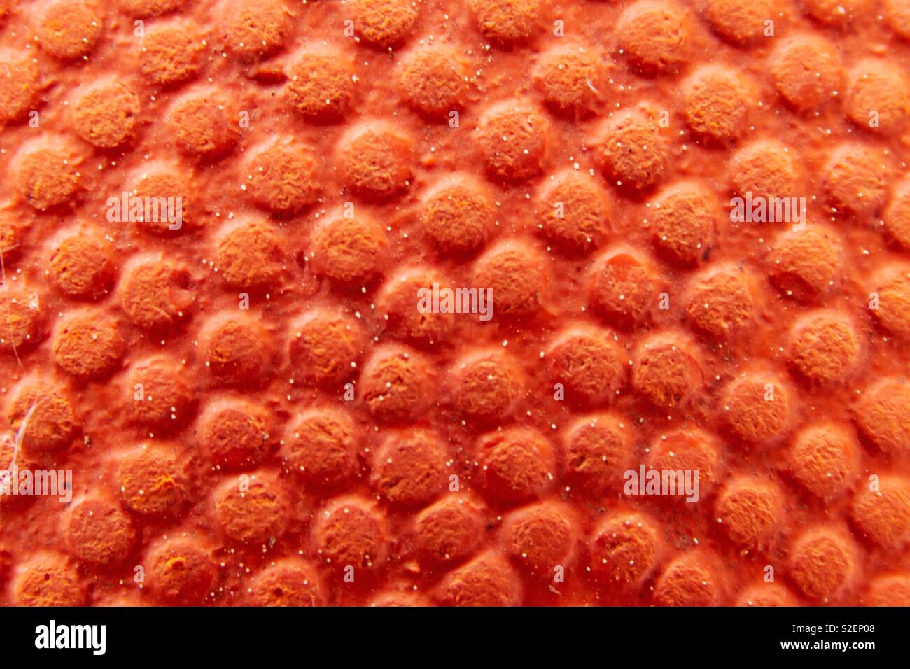 the close-up of a used orange basketball shows small grains of sand ...