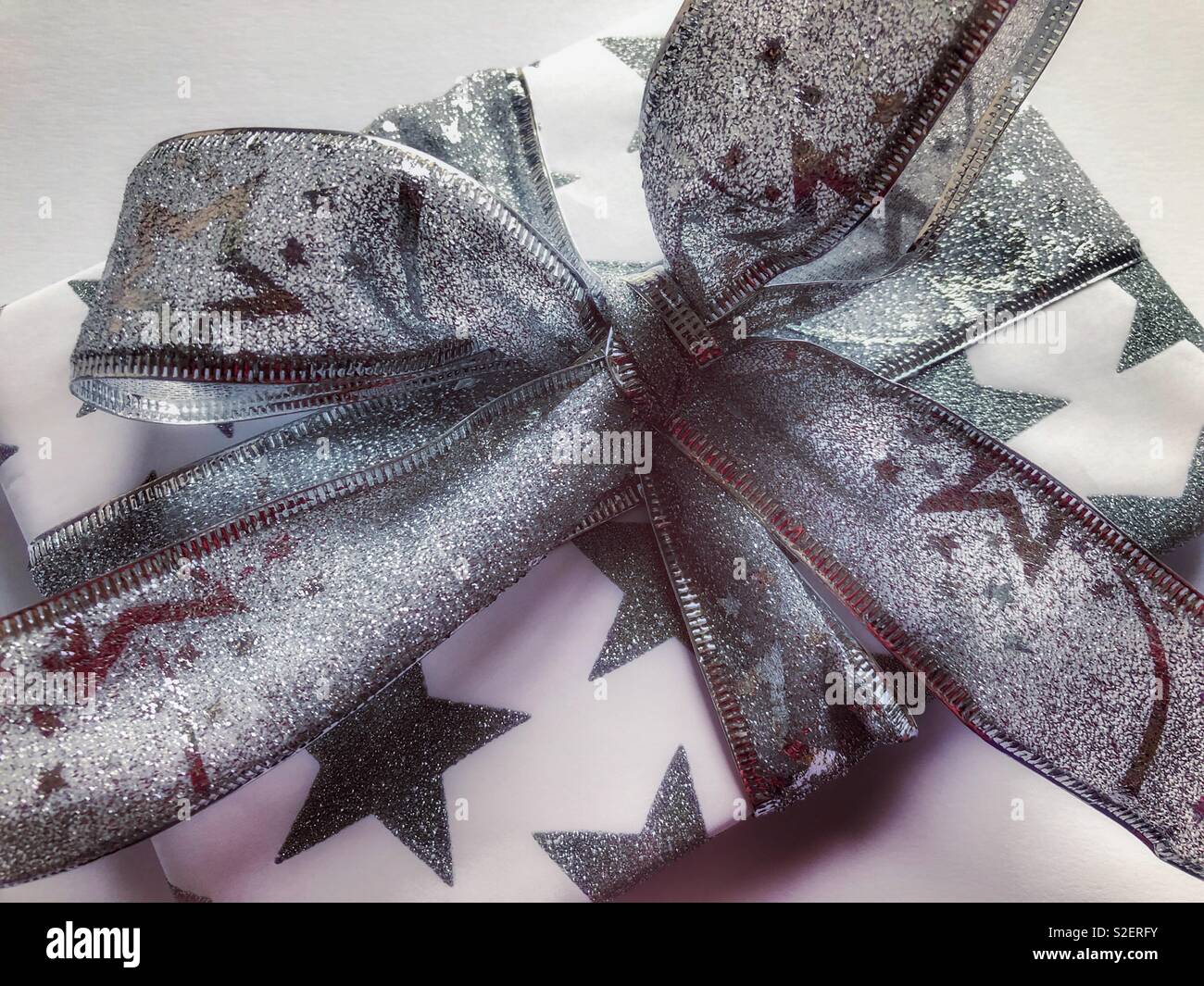 Christmas present decorated with a silver ribbon tied in a flamboyant ...