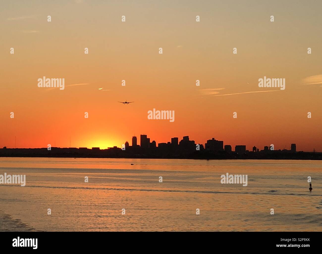 Boston Sunset from the water with plane flying overhead Stock Photo - Alamy