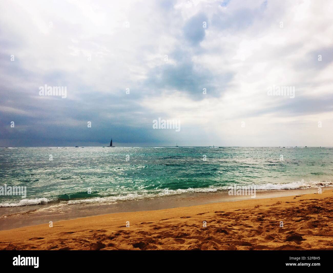 Warm ocean seen from a sandy beach on a hot overcast day in Hawaii ...