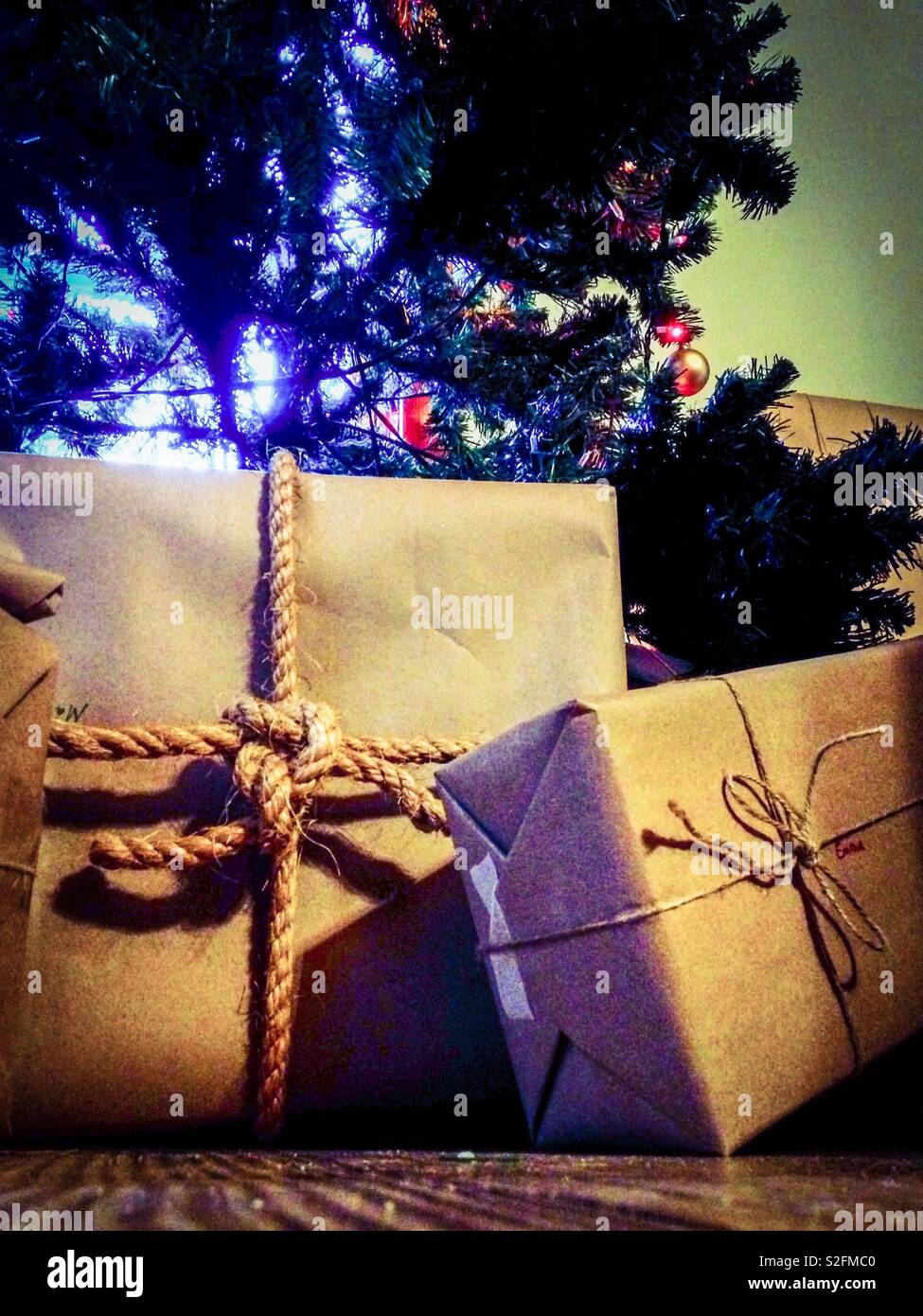Brown paper wrapped gifts under the Christmas tree Stock Photo - Alamy