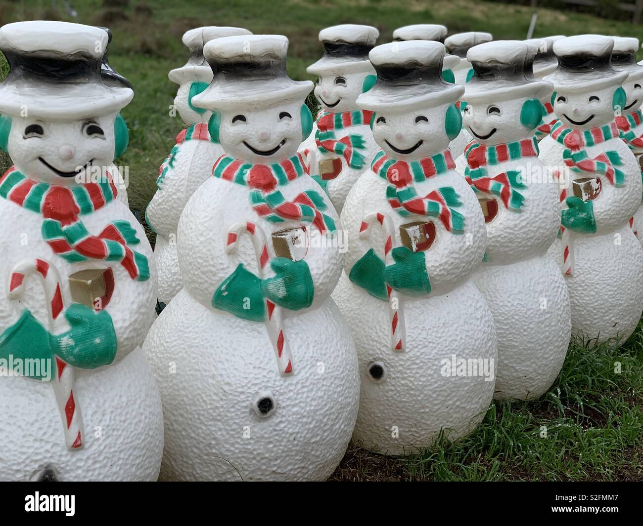Two rows of plastic snowmen dressed is green and red earmuffs scarf and ...