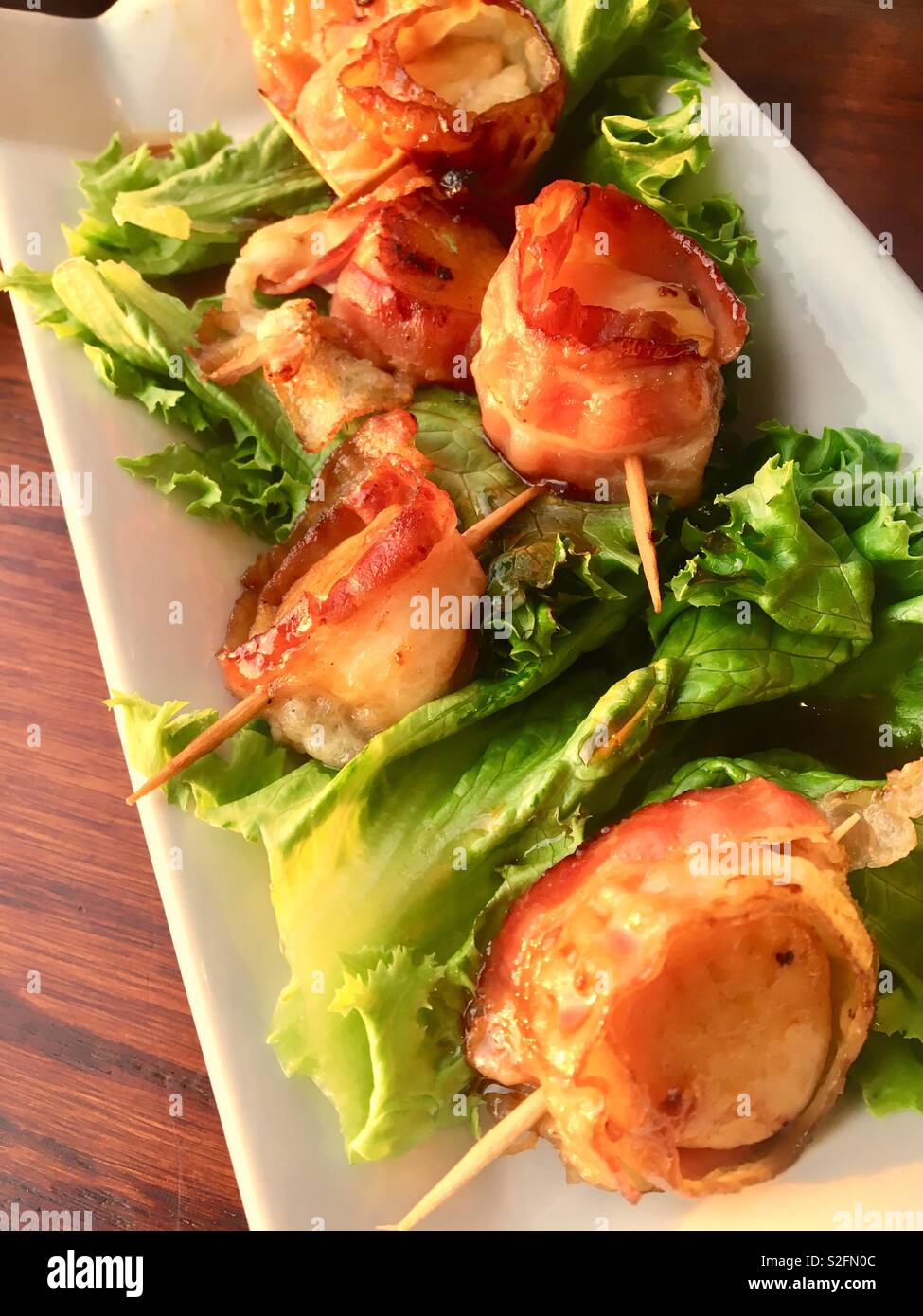 Bacon wrapped scallops with lettuce Stock Photo - Alamy