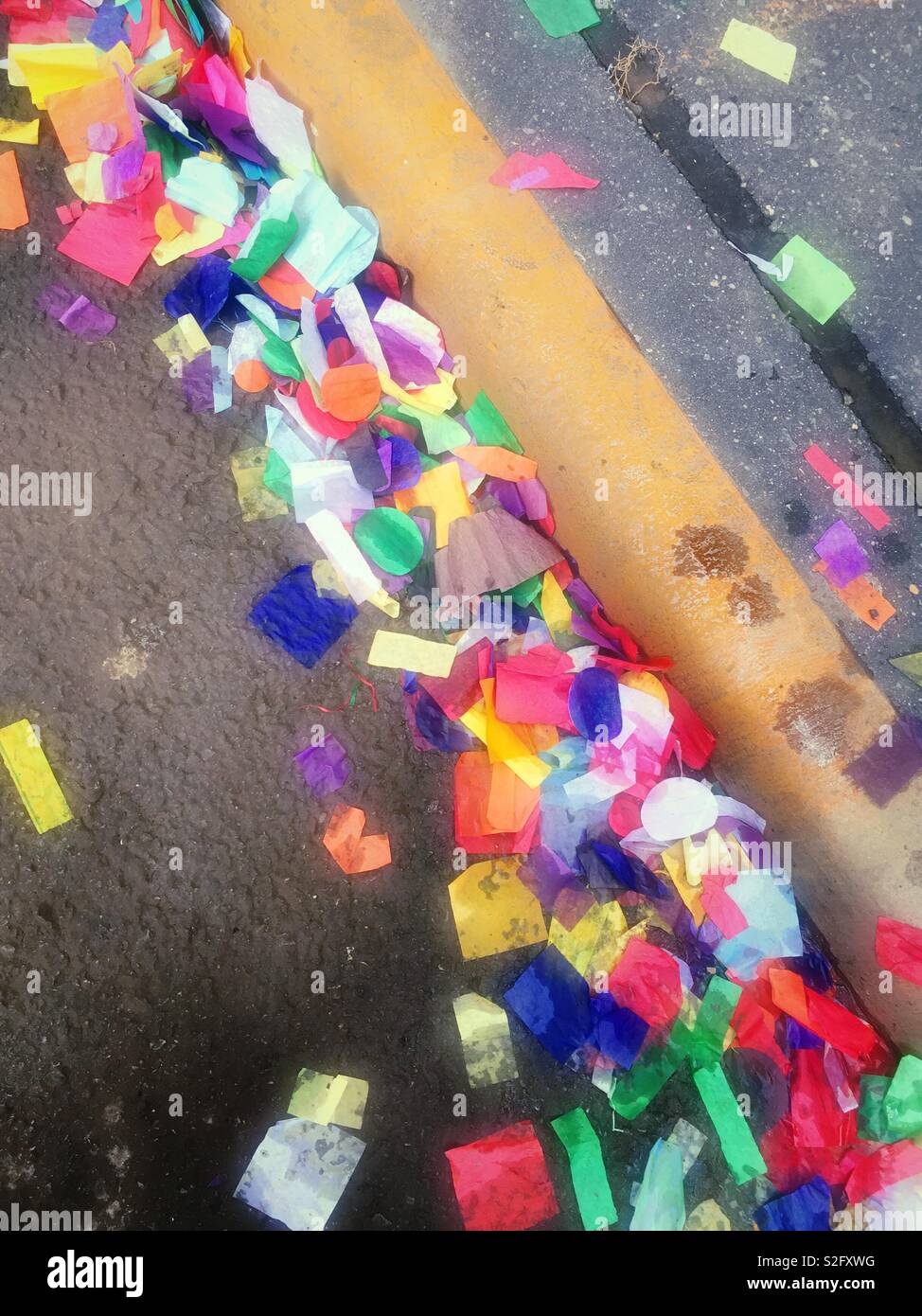 Brightly colored paper confetti in a New York city street and curb, NYC ...