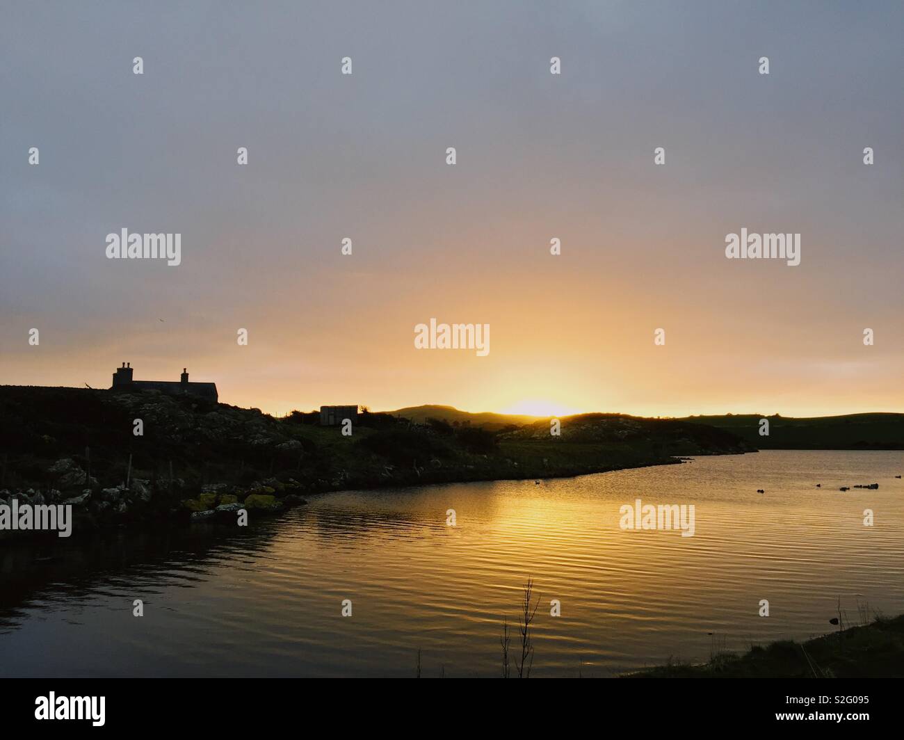 Sun setting over Cemlyn Bay lagoon, Anglesey, North Wales Stock Photo ...