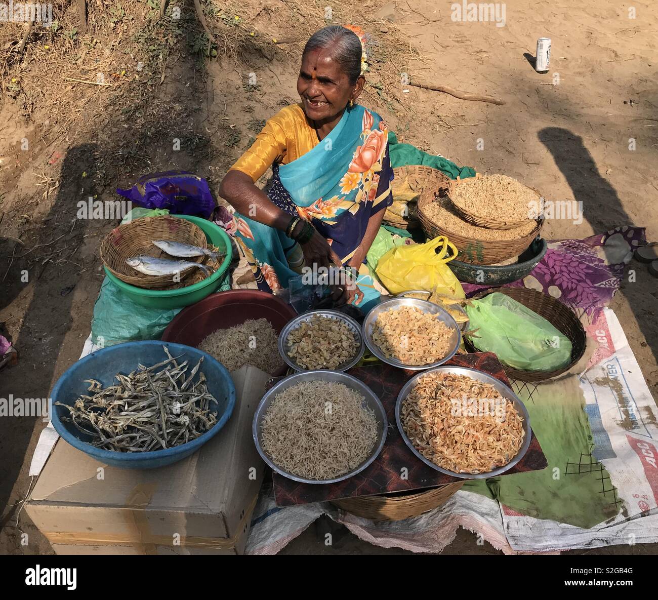 And elderly local lady of Alibaug seels dry fish on beach near Alibaug ...