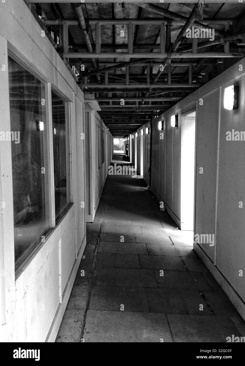 The view along a long dark pedestrian walkway adjacent to a building ...