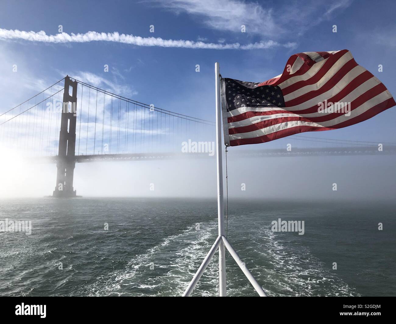 An American flag flaps in the wind on a foggy day under the Golden Gate ...