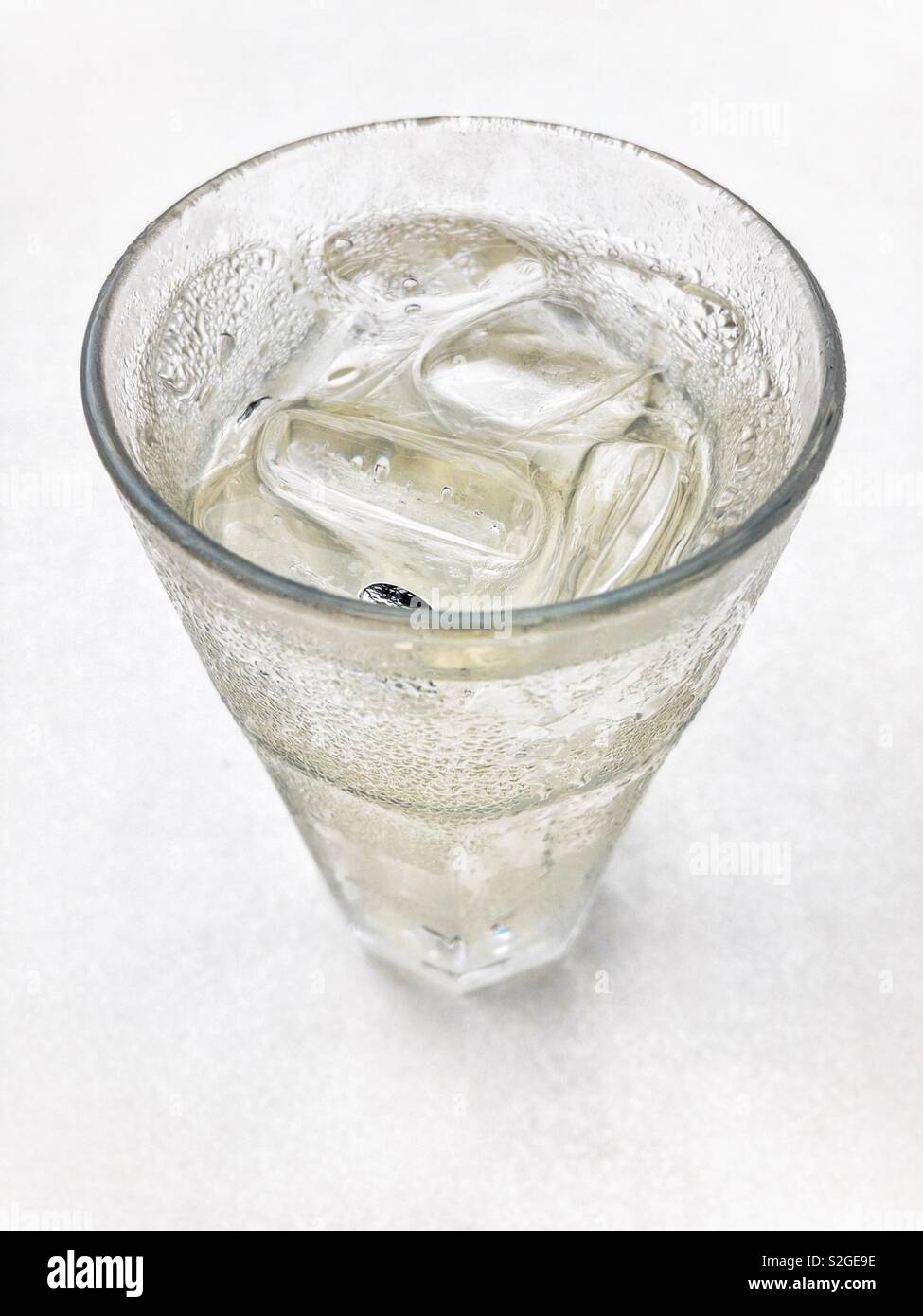 Glass full of cold soda water and ice cubes on a white background Stock ...