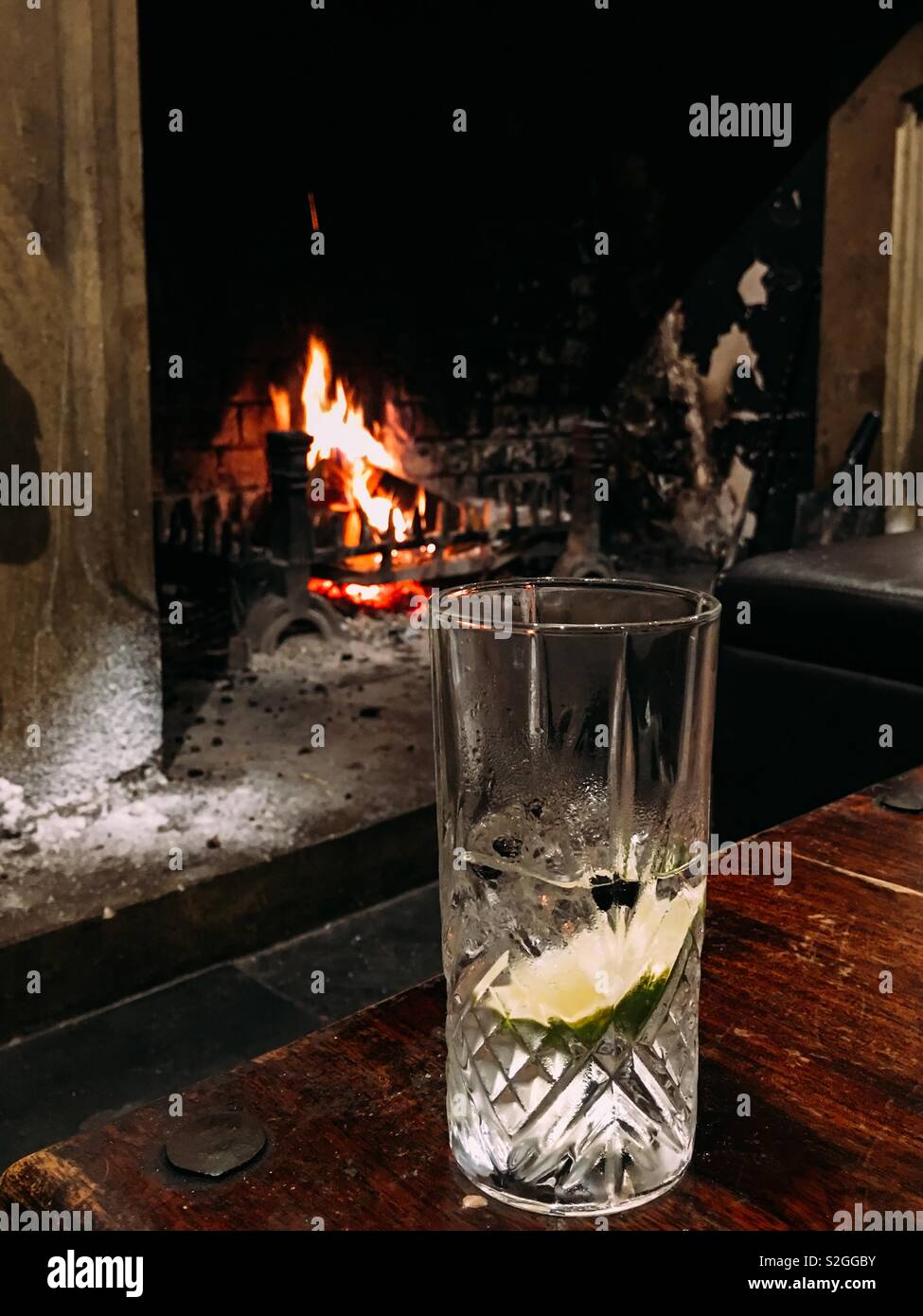 Gin and tonic in front of a fire Stock Photo - Alamy
