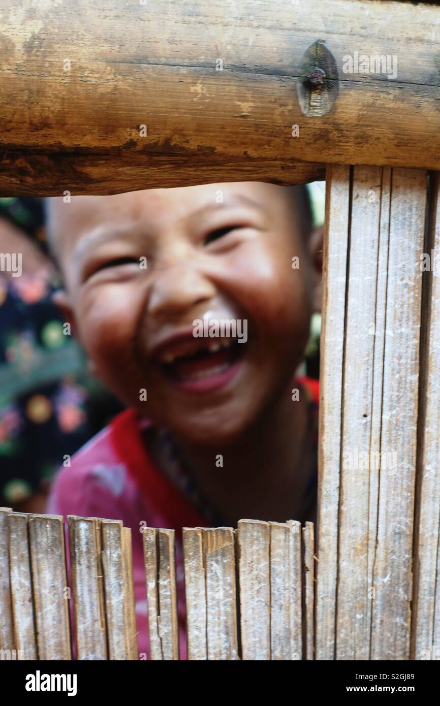 Lahu hilltribe: laughing child hiding behind a bamboo fence Stock Photo ...