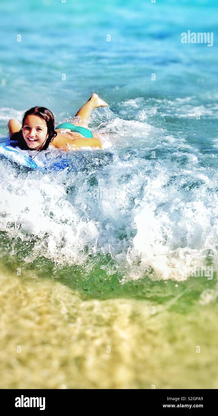 Girl surfing waves on a beach Stock Photo - Alamy