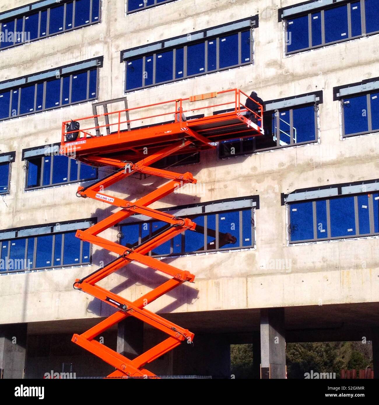 Workers lay windows on a building at a lifting platform Stock Photo - Alamy