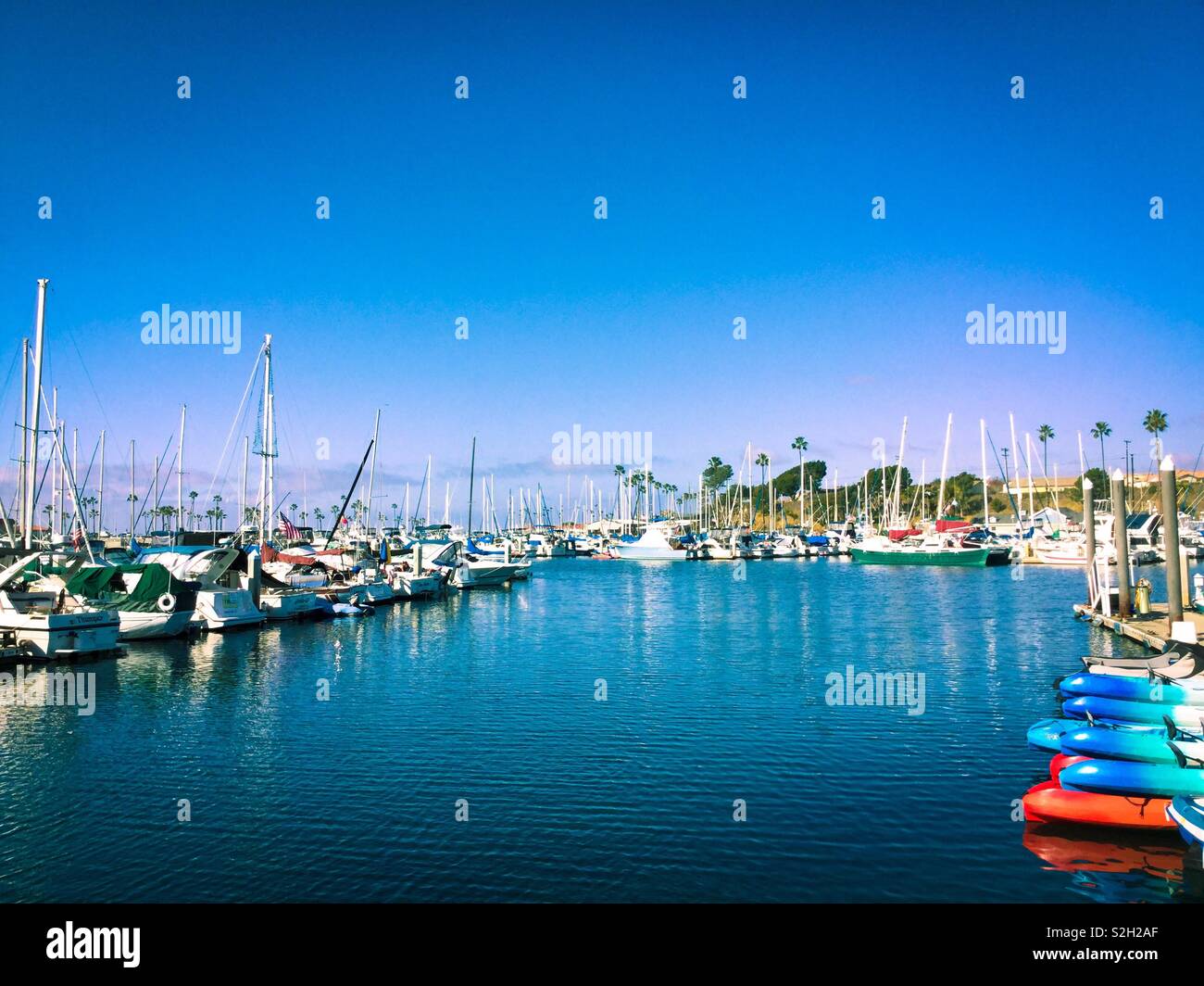 Blue water, harbor with docked boats under blue sky Stock Photo - Alamy