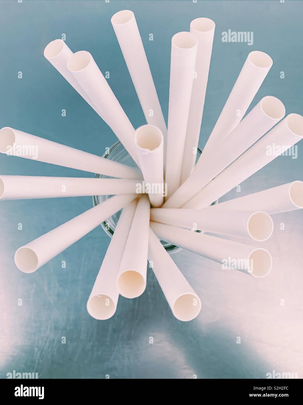 Close up looking down at paper straws in a glass container on stainless ...