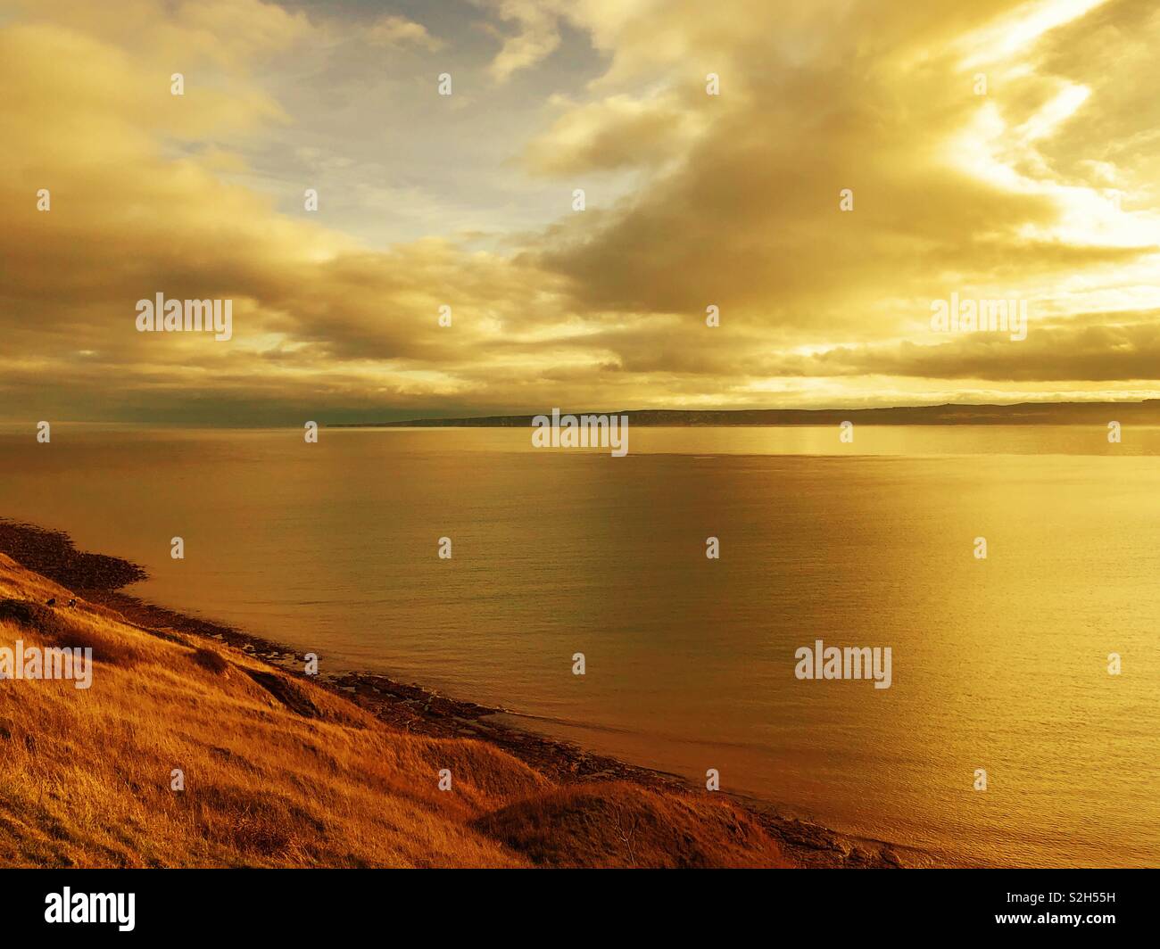 Sunrise over a flat calm sea Stock Photo - Alamy