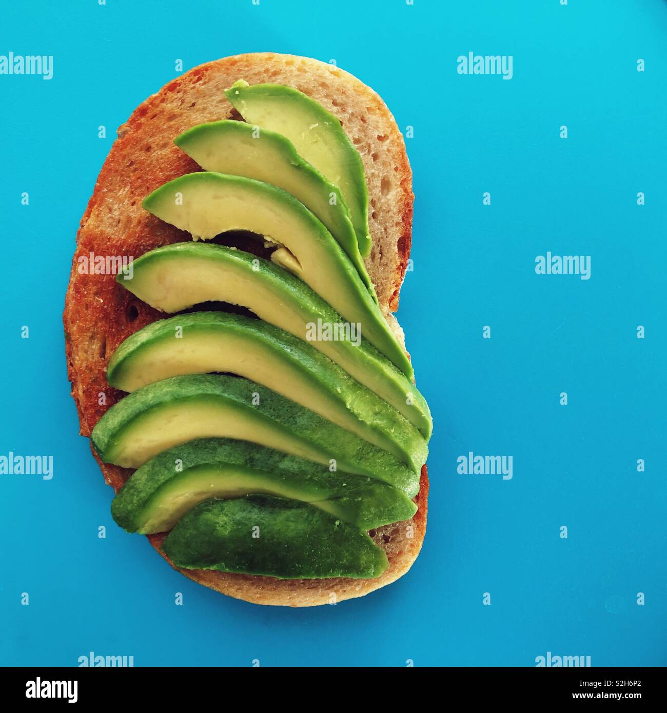 Sliced avocado on rye toast with bright blue background Stock Photo - Alamy