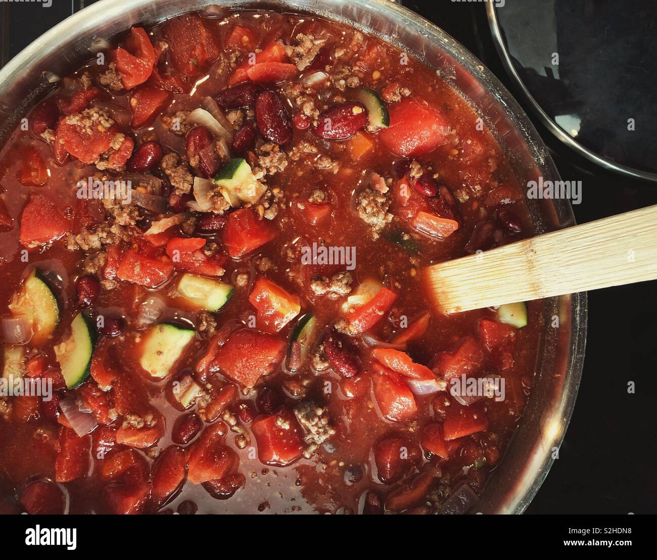 Cooking homemade beef and vegetable chilli in a stainless steel pot ...