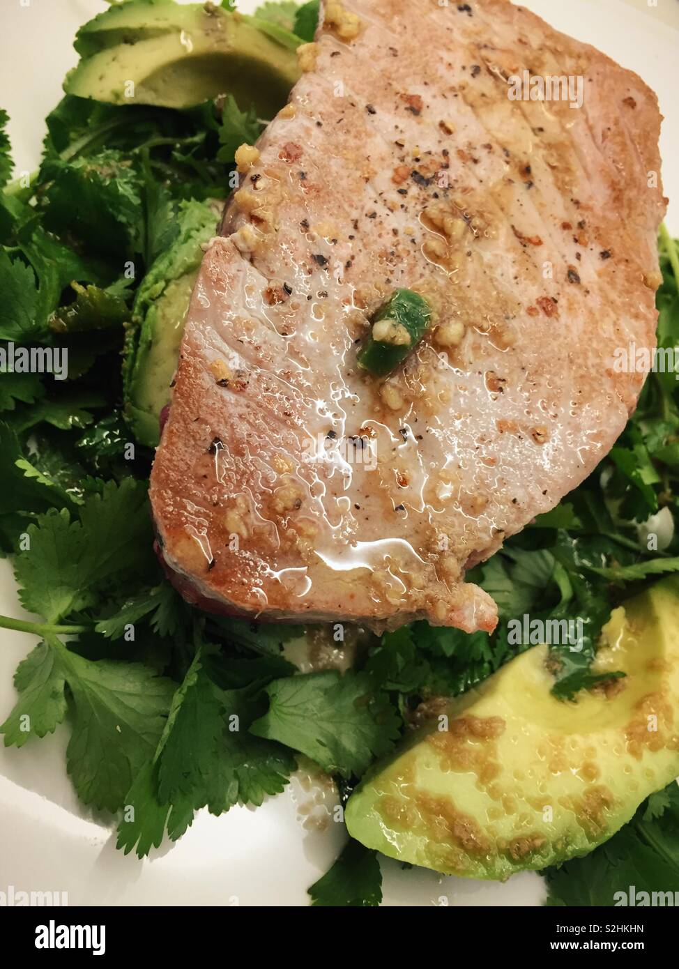 Close up of a gourmet entrée of seared fresh tuna on a bed of avocado ...