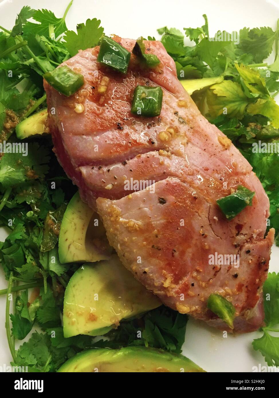 Close up of a gourmet entrée of seared fresh tuna on a bed of avocado ...