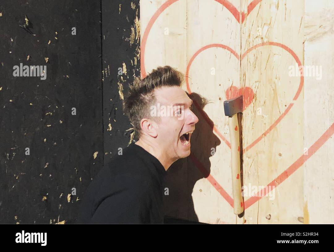 Man screaming at axe in centre of heart shaped target Stock Photo - Alamy