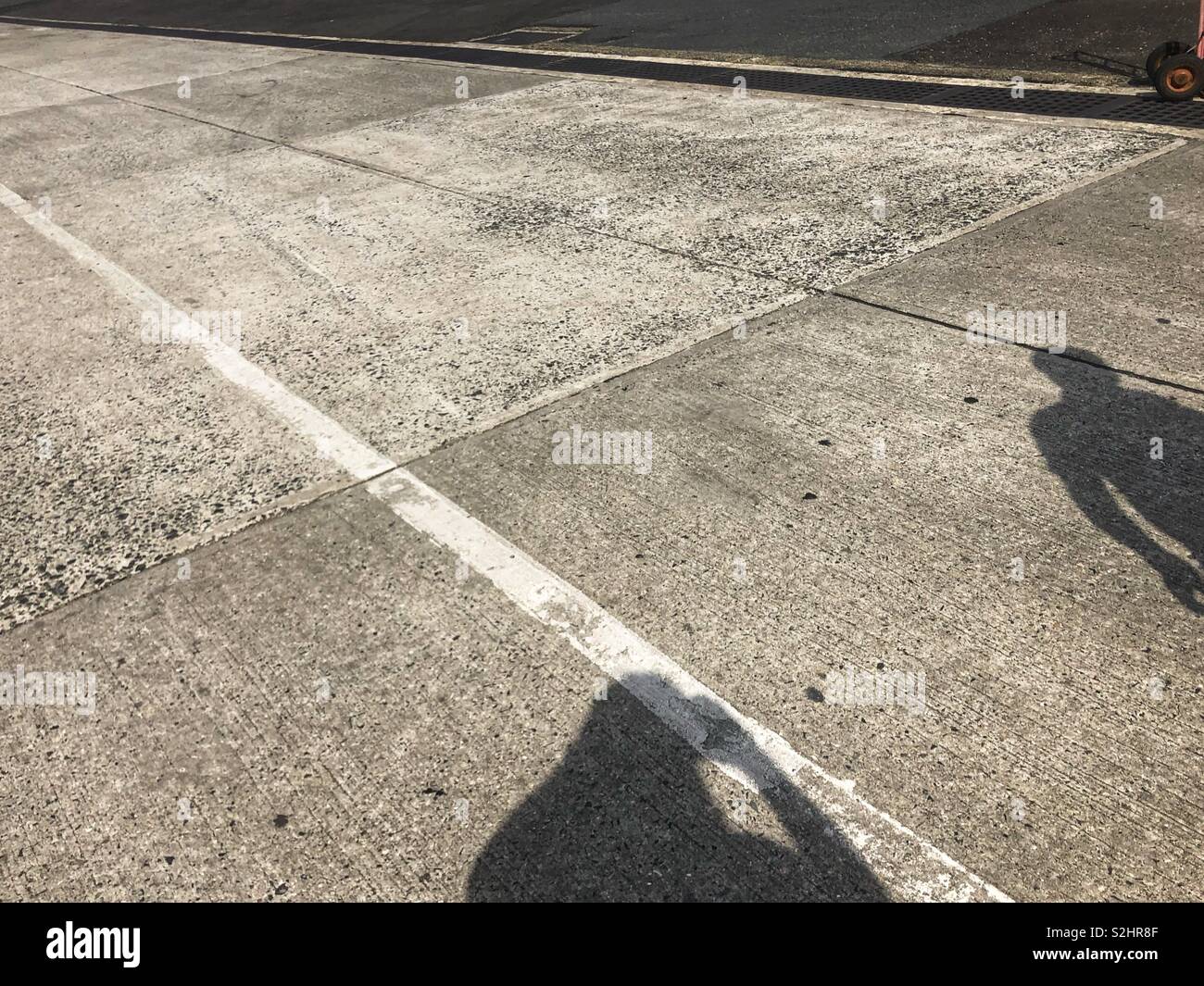 Shadow of a woman taking a picture of a man at the sunny airport tarmac ...