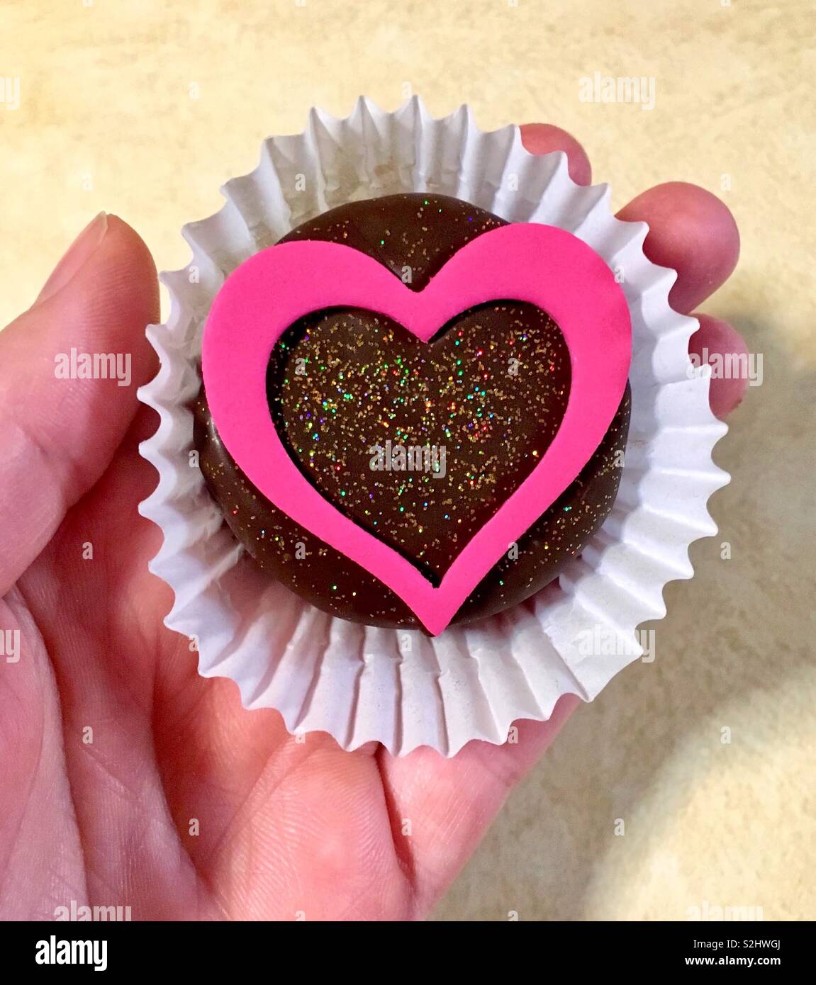 Person holding chocolate dipped Oreo with edible rainbow glitter and ...