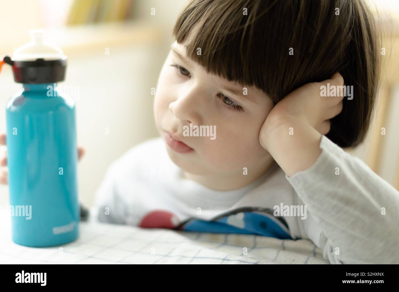 Sad boy is sitting on chair and holding bottle Stock Photo - Alamy